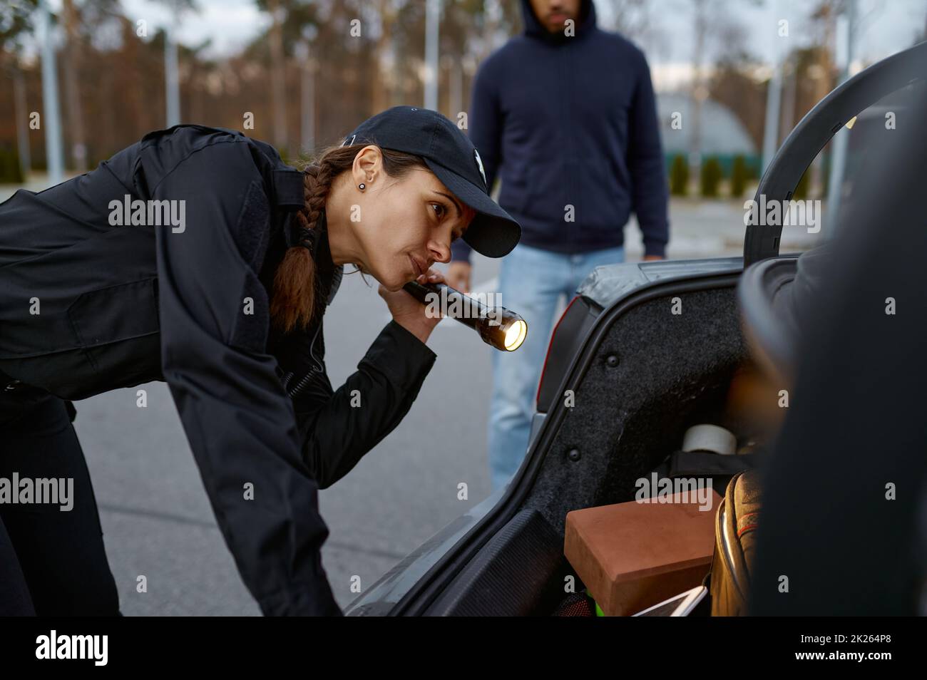 Woman police officer inspecting car with flashlight Stock Photo - Alamy