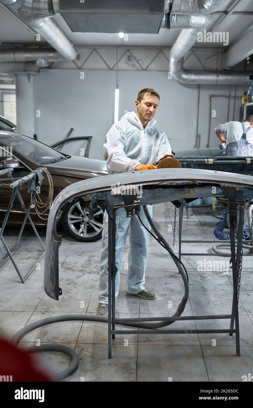 Serviceman polishing car body part in workshop Stock Photo - Alamy