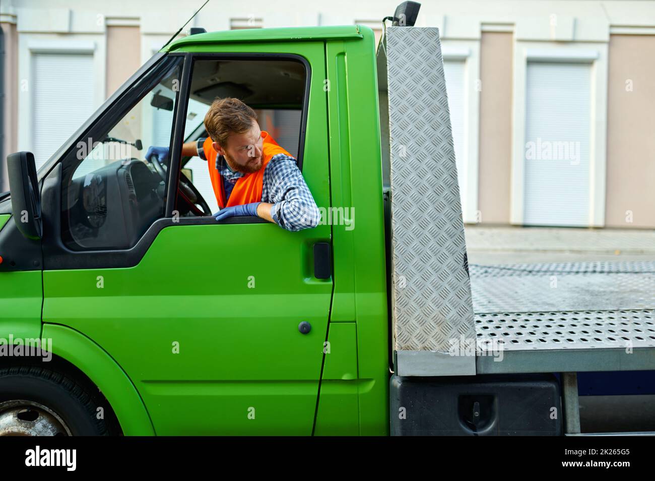 Tow truck driver transporting car down street Stock Photo - Alamy