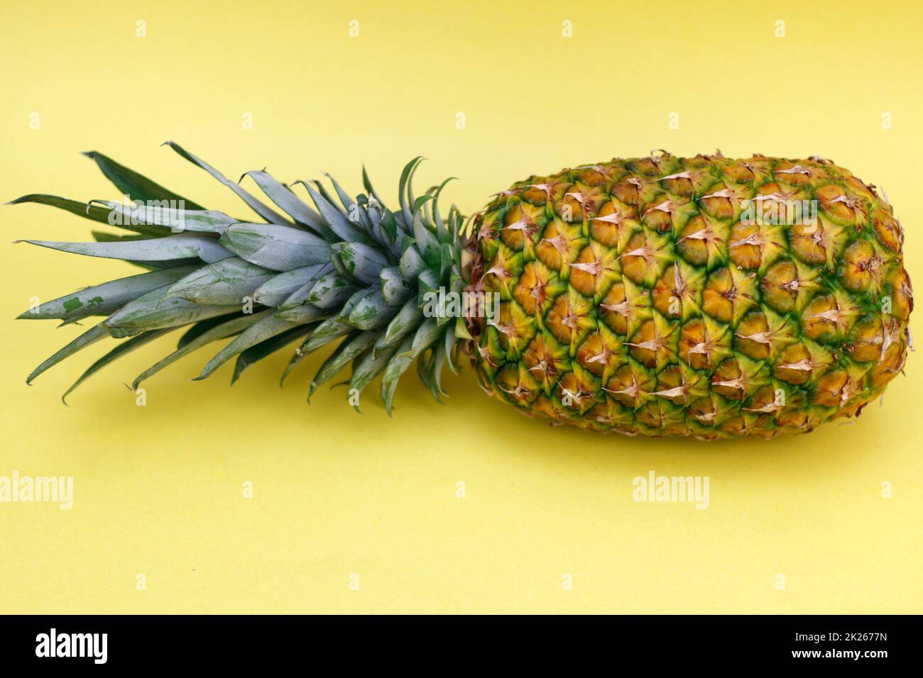 Whole Pineapple with Top Laying Sideways on Yellow Background Stock ...