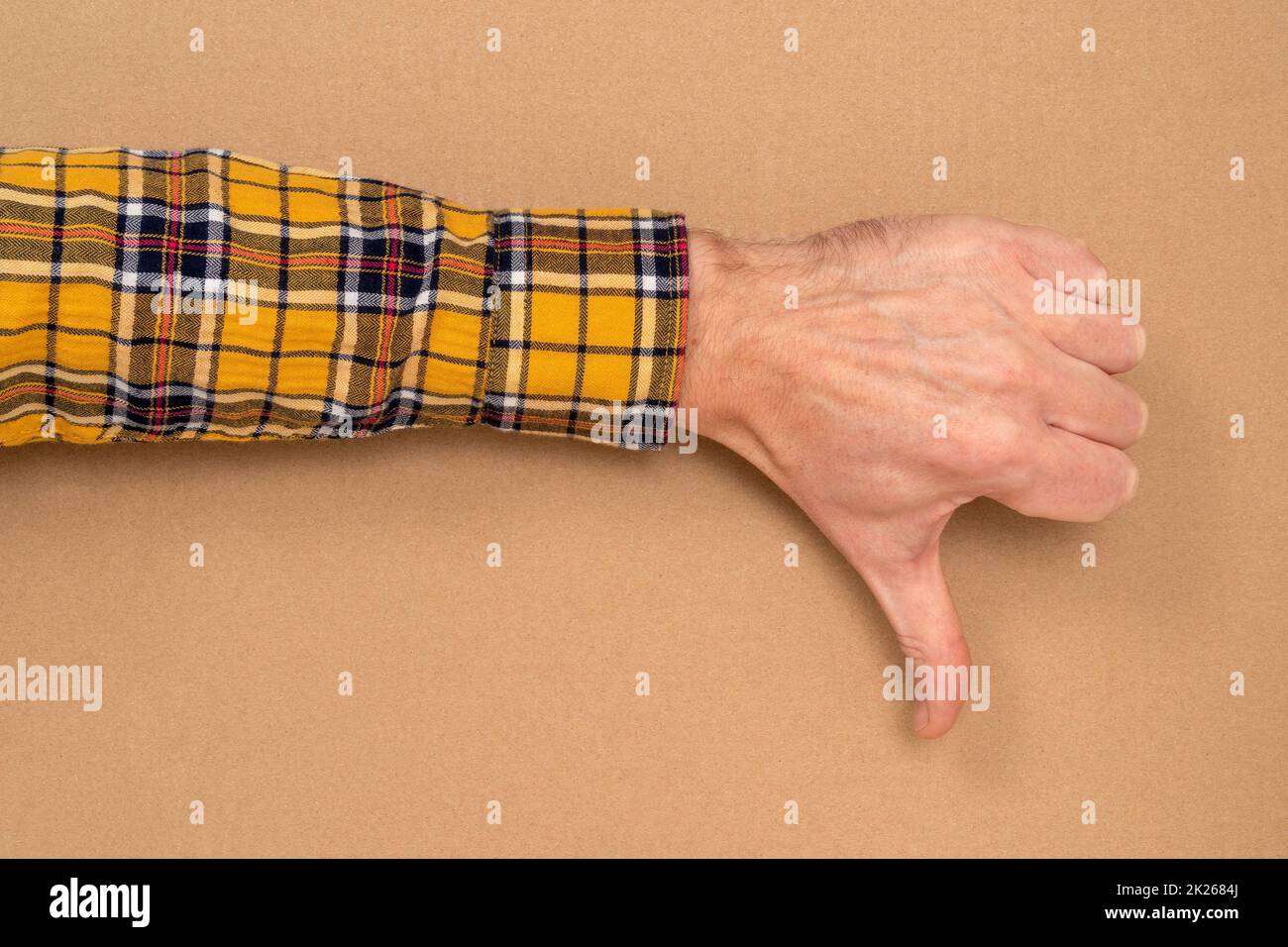 Hand with thumb down on a brown paper background Stock Photo - Alamy