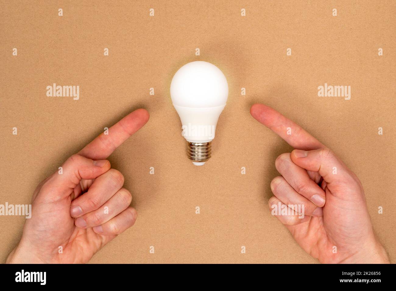 Hands pointing to glowing light bulb Stock Photo - Alamy