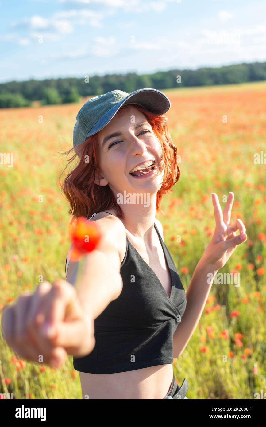 happy young girl with poppy flower showing victory sign Stock Photo - Alamy