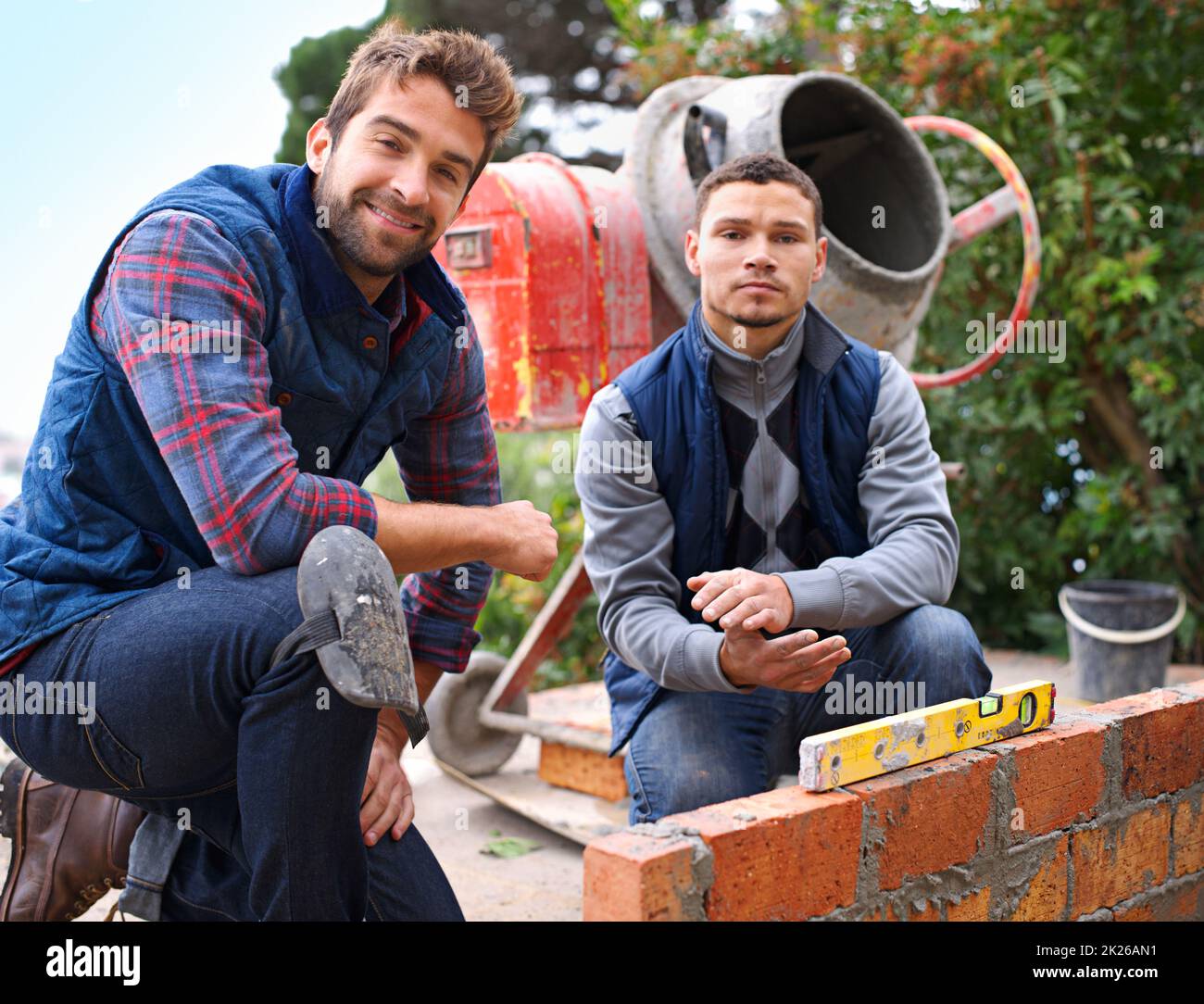 Making strong foundations. Portrait of a bricklayer and his apprentice ...