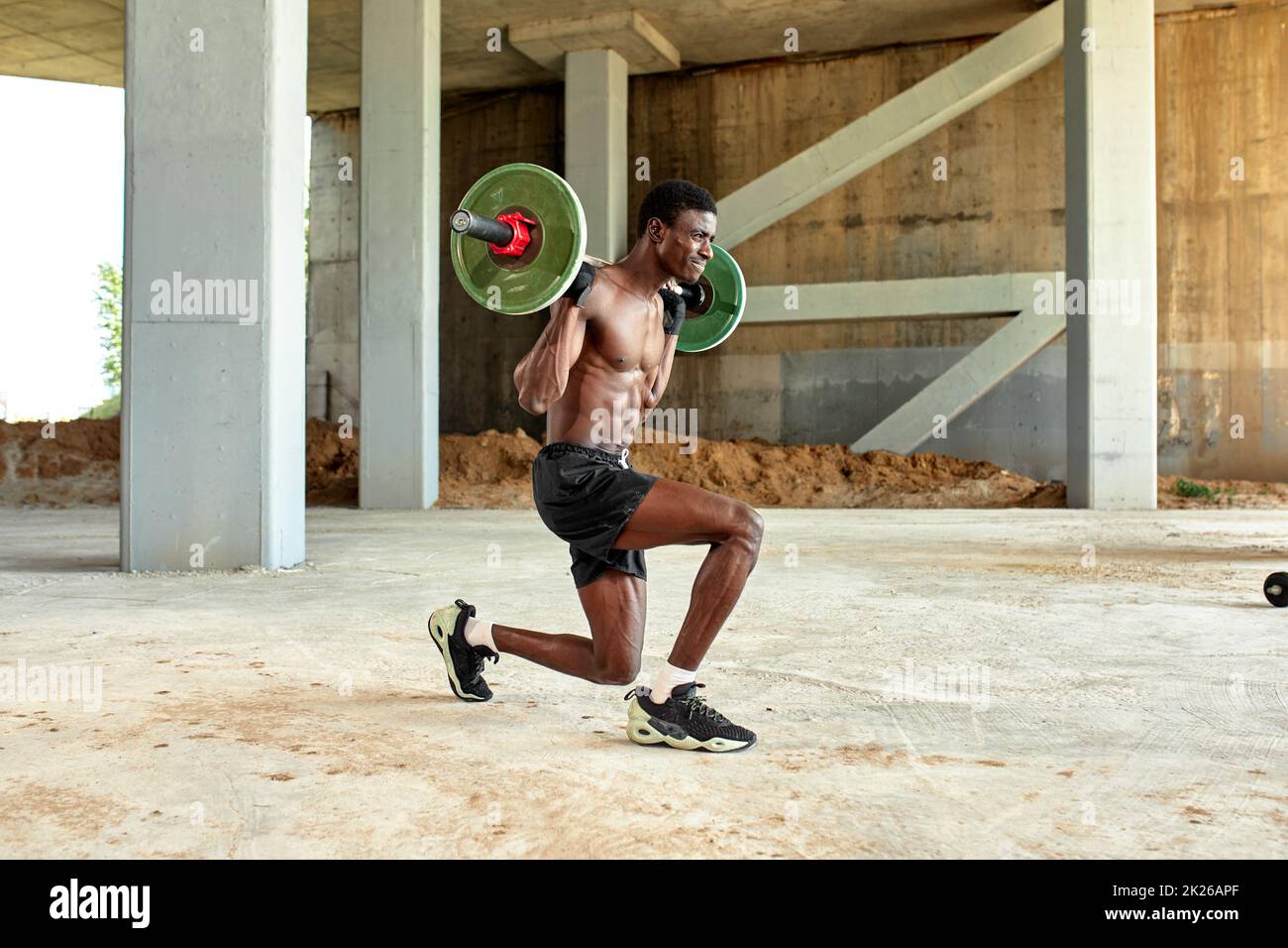 Athletic black young man lifting a heavy-weight barbell in outdoor gym ...