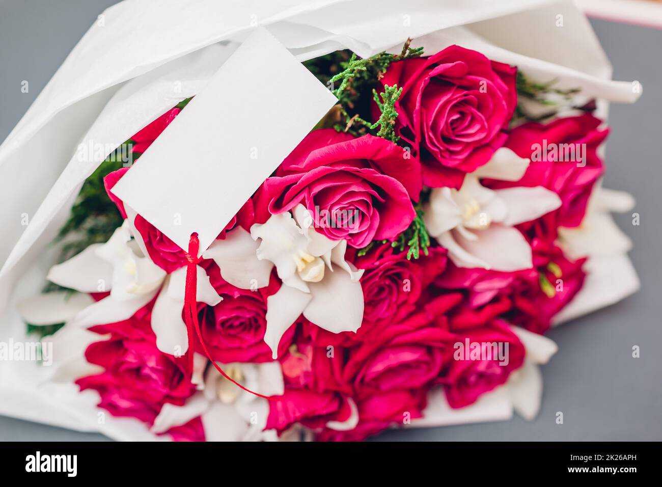 Bouquet of red roses and white orchids with blank note. Present gift ...