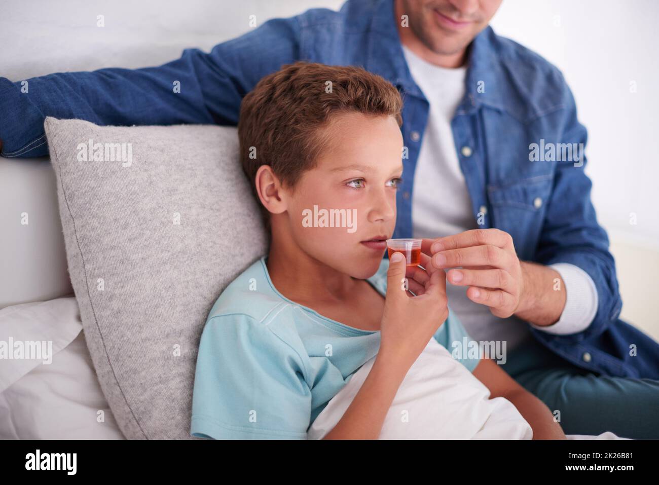 This will fix that flu. a caring father giving his sick little boy some ...