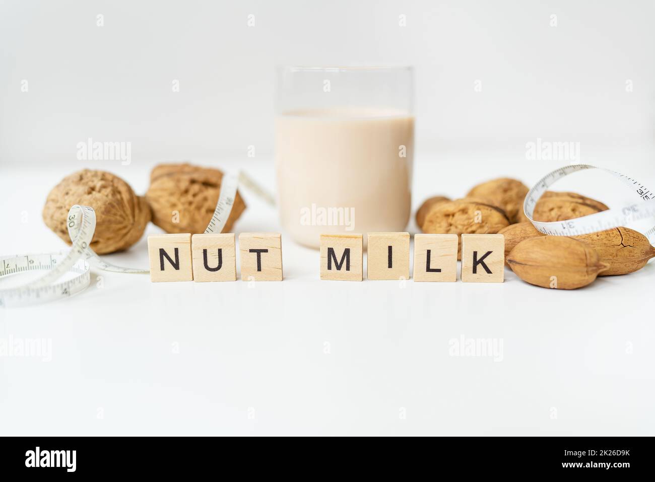 Vegan milk from nuts in a glass cup with various nuts on a white table ...