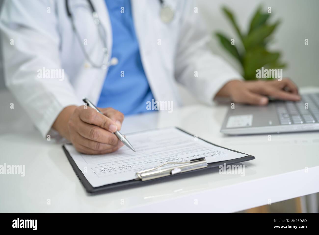 Doctor write health medical note in clipboard with laptop in hospital ...