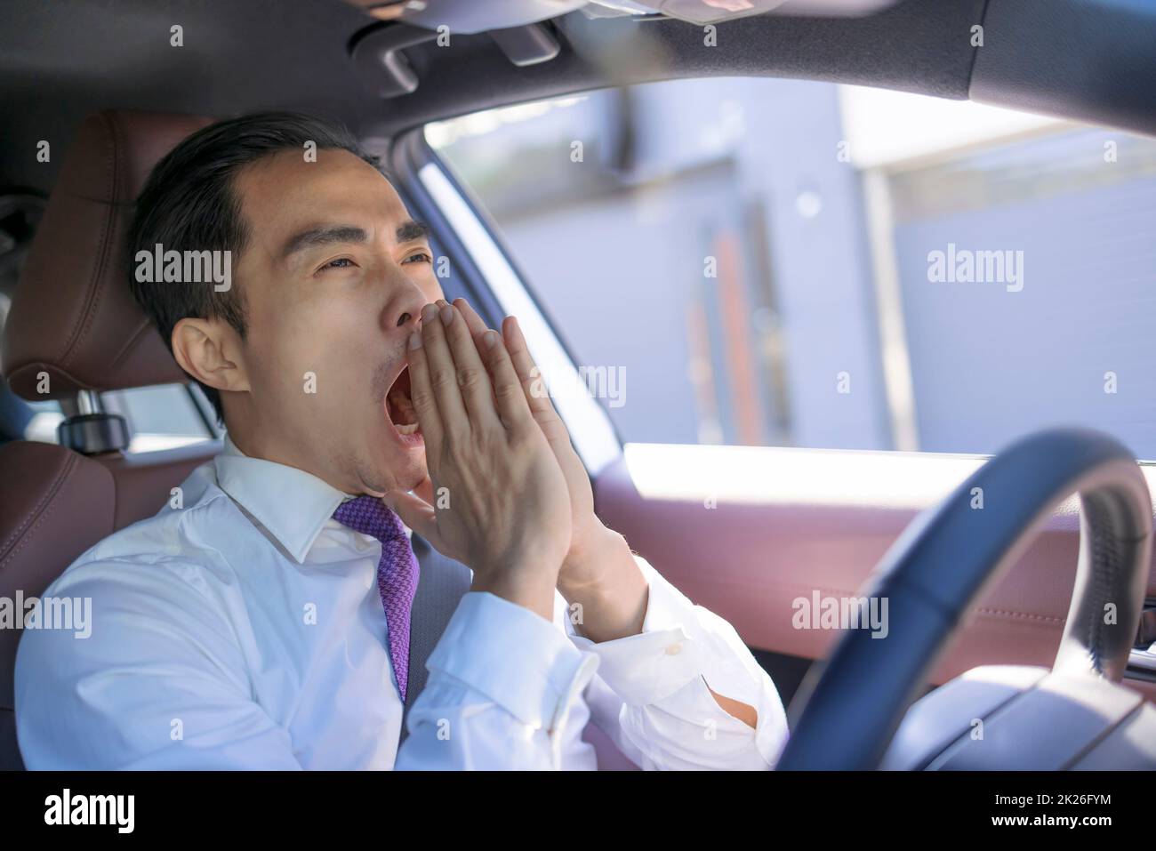 Young businessman looks tired yawning while driving the car Stock Photo ...