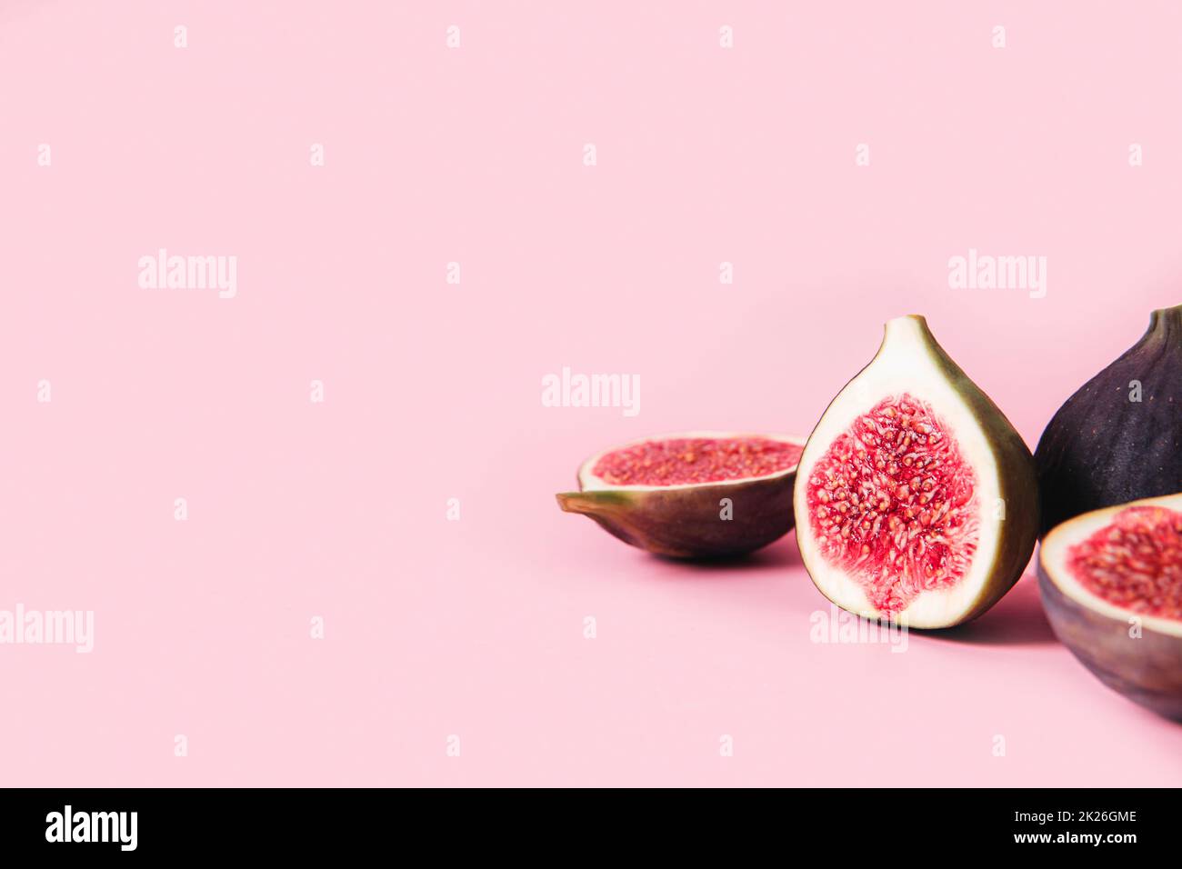 Fresh tasty fig fruit halves with shadow laying down on pink background ...
