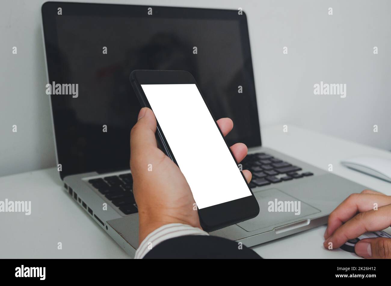 Businessman holding smart phone mock up white screen and computer ...