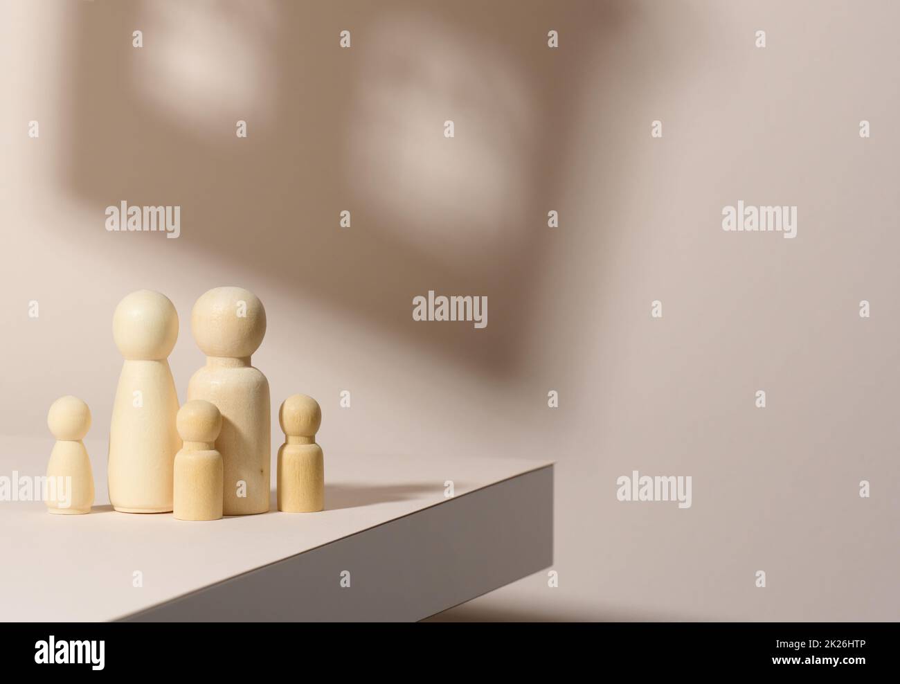 wooden figurines of a family on a background of shadow in the form of a ...