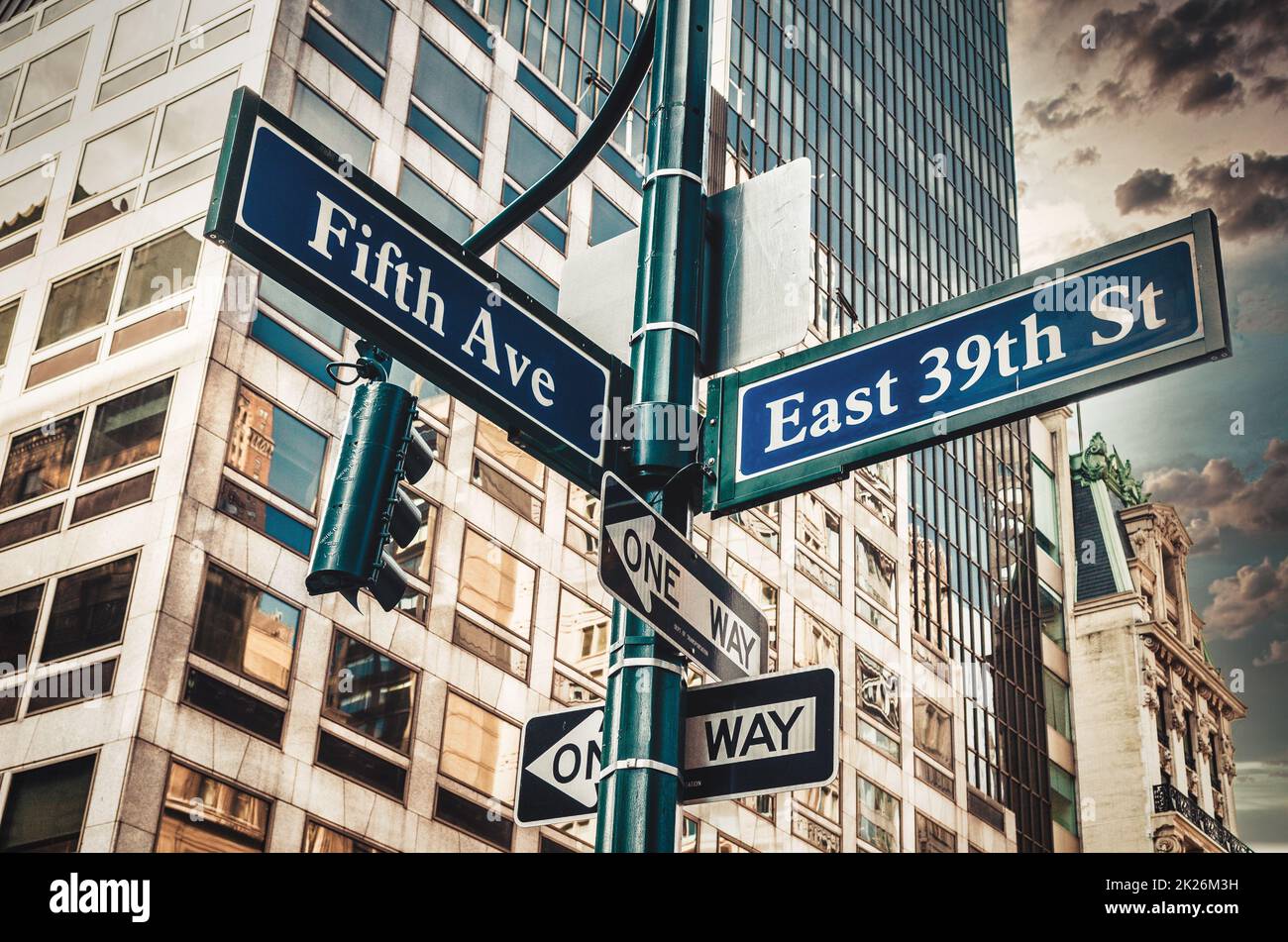 Fifth Ave 5th Ave, New York City sign, view from low angle with sunset and skyscraper in ...