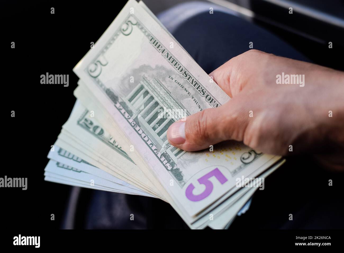 man hands over money in a car. A wad of dollars in his hand Stock Photo ...