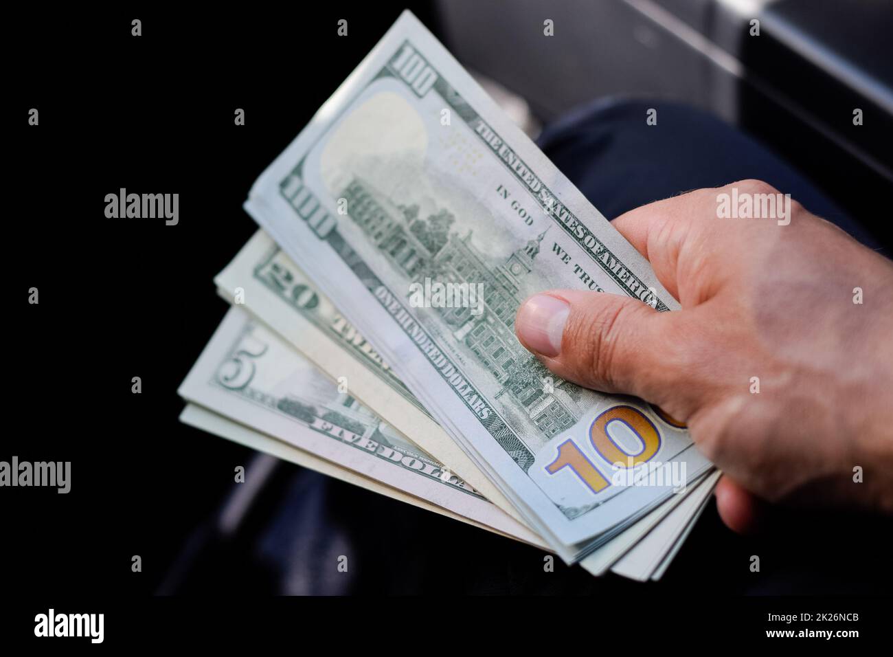 man hands over money in a car. A wad of dollars in his hand Stock Photo ...