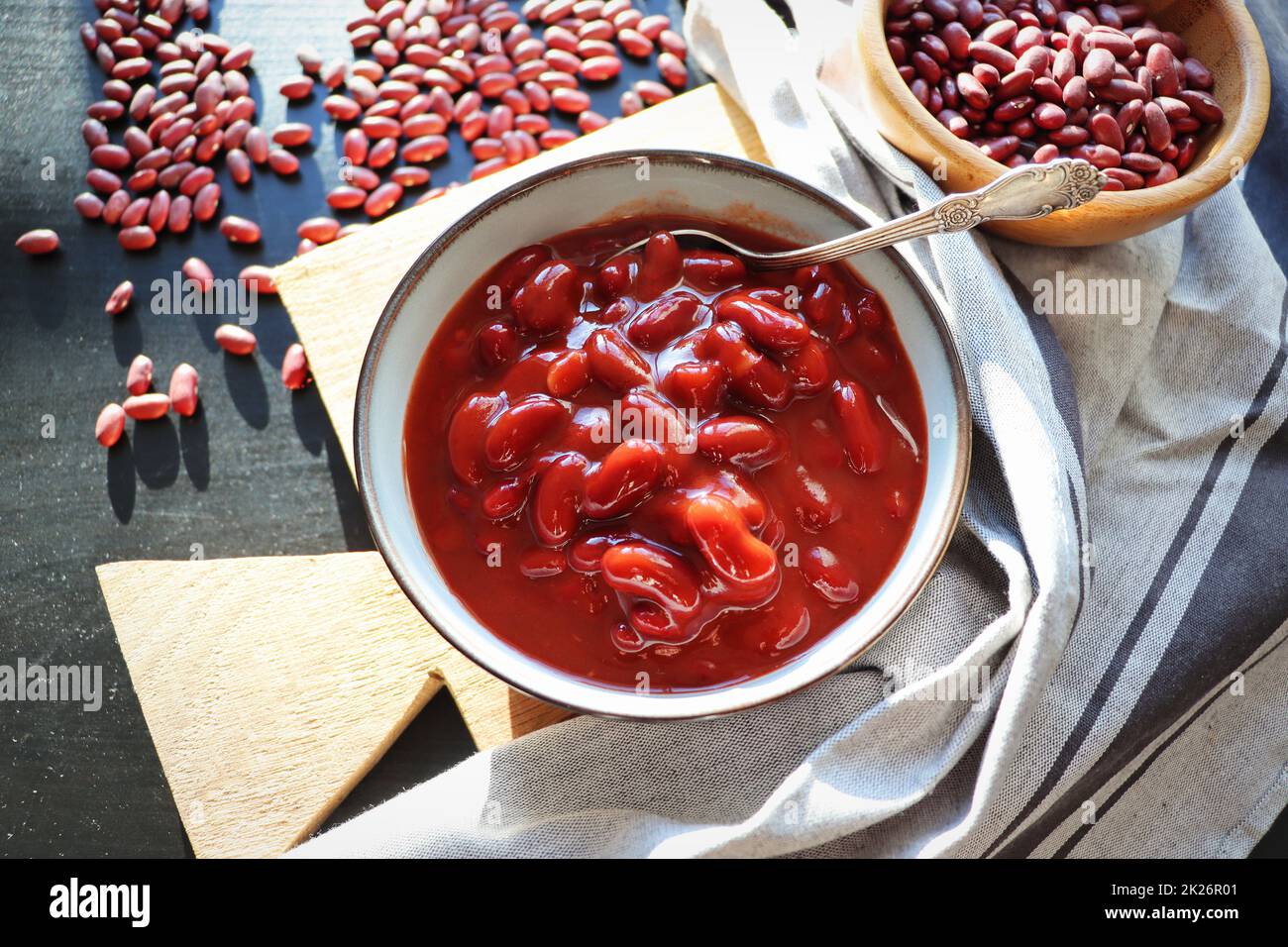 Raw and canned red kidney chilli beans in bowl on a rustic wooden table ...