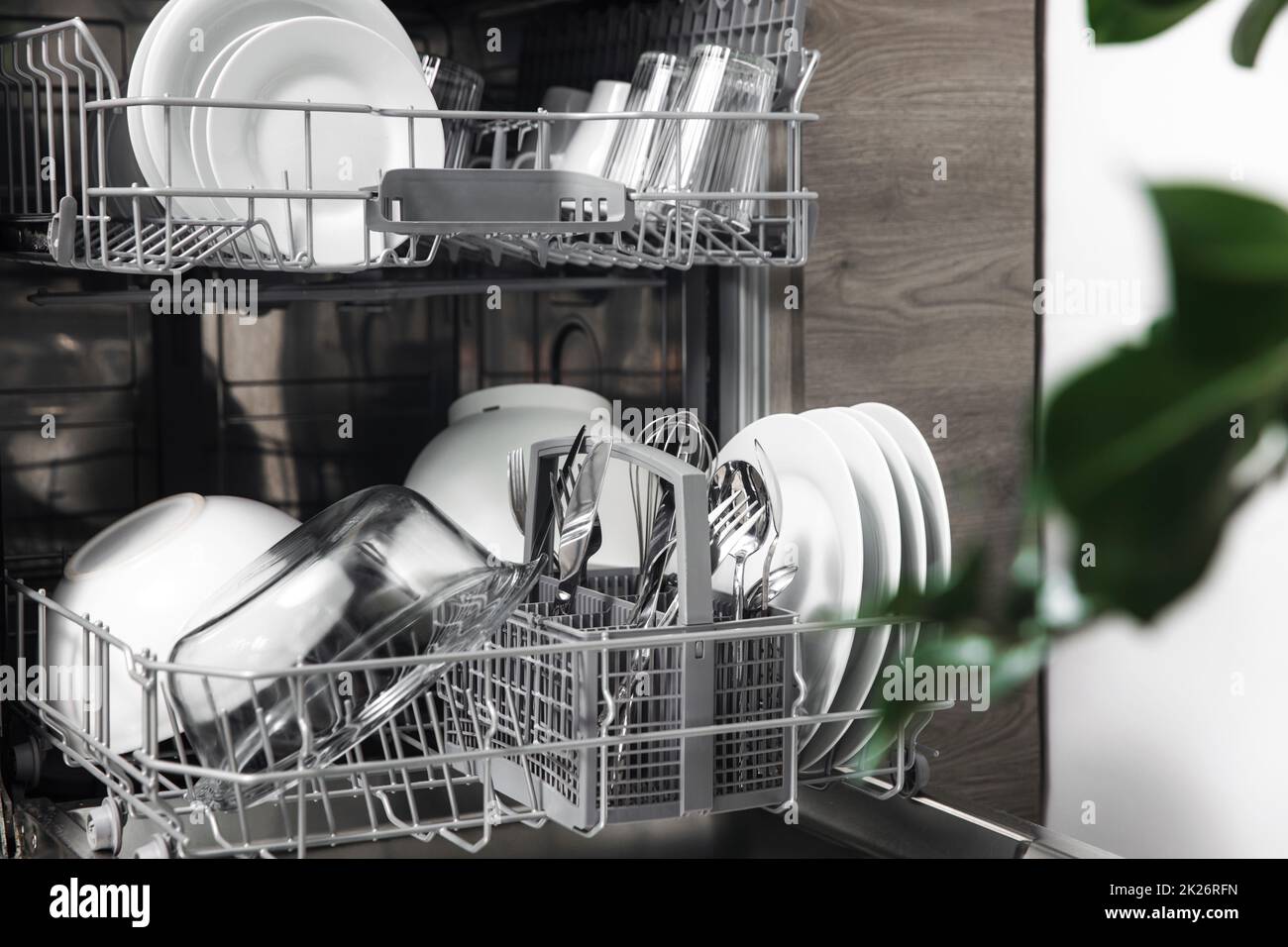 Open dishwasher with clean utensil inside, cutlery, glasses, dishes at ...