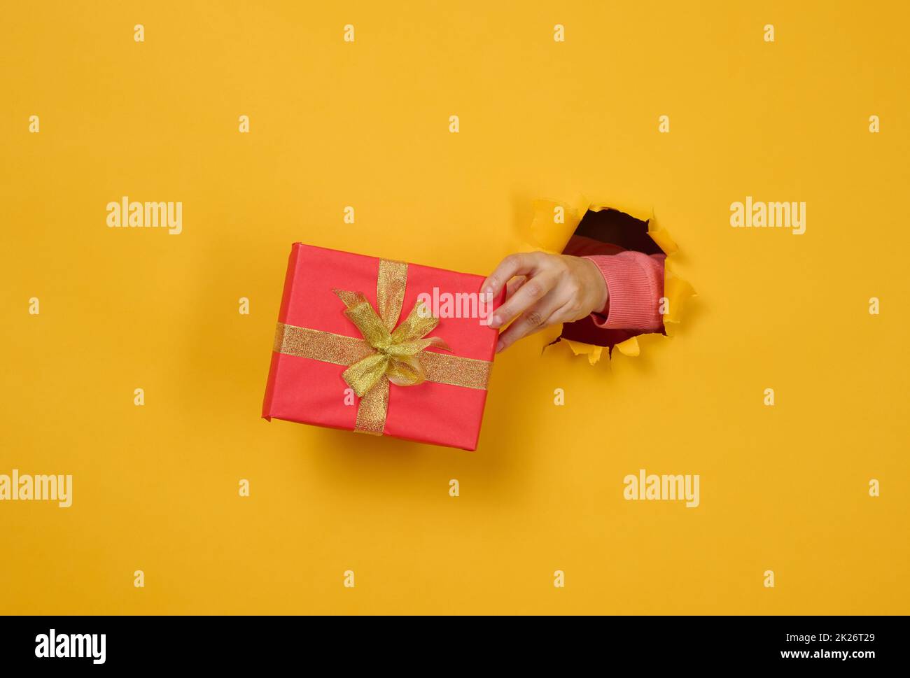 female hand holds a box with a gift on a yellow background, part of the ...