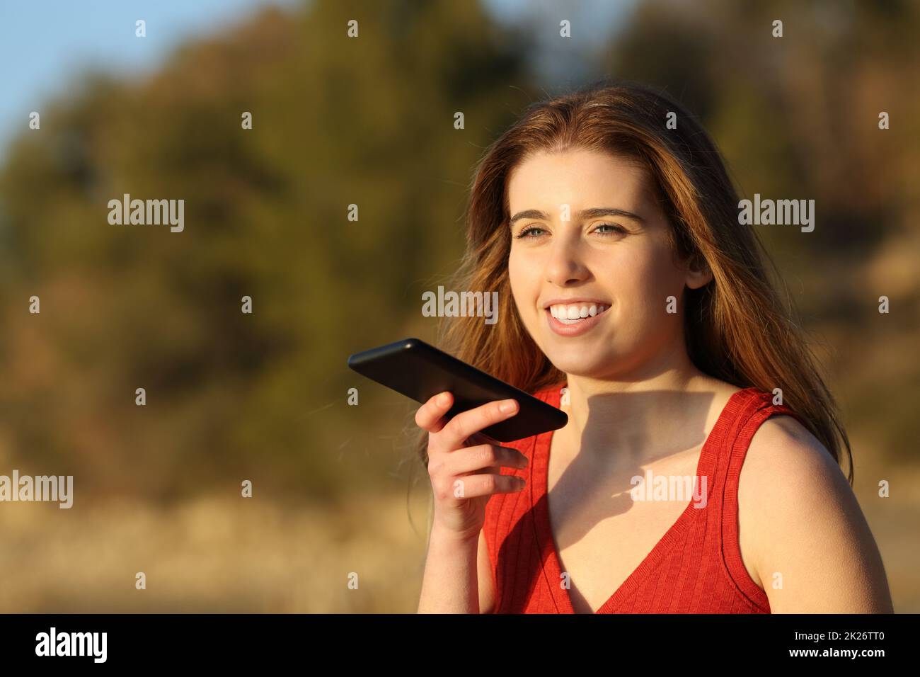 Happy woman in red using voice recognition dictating message Stock ...