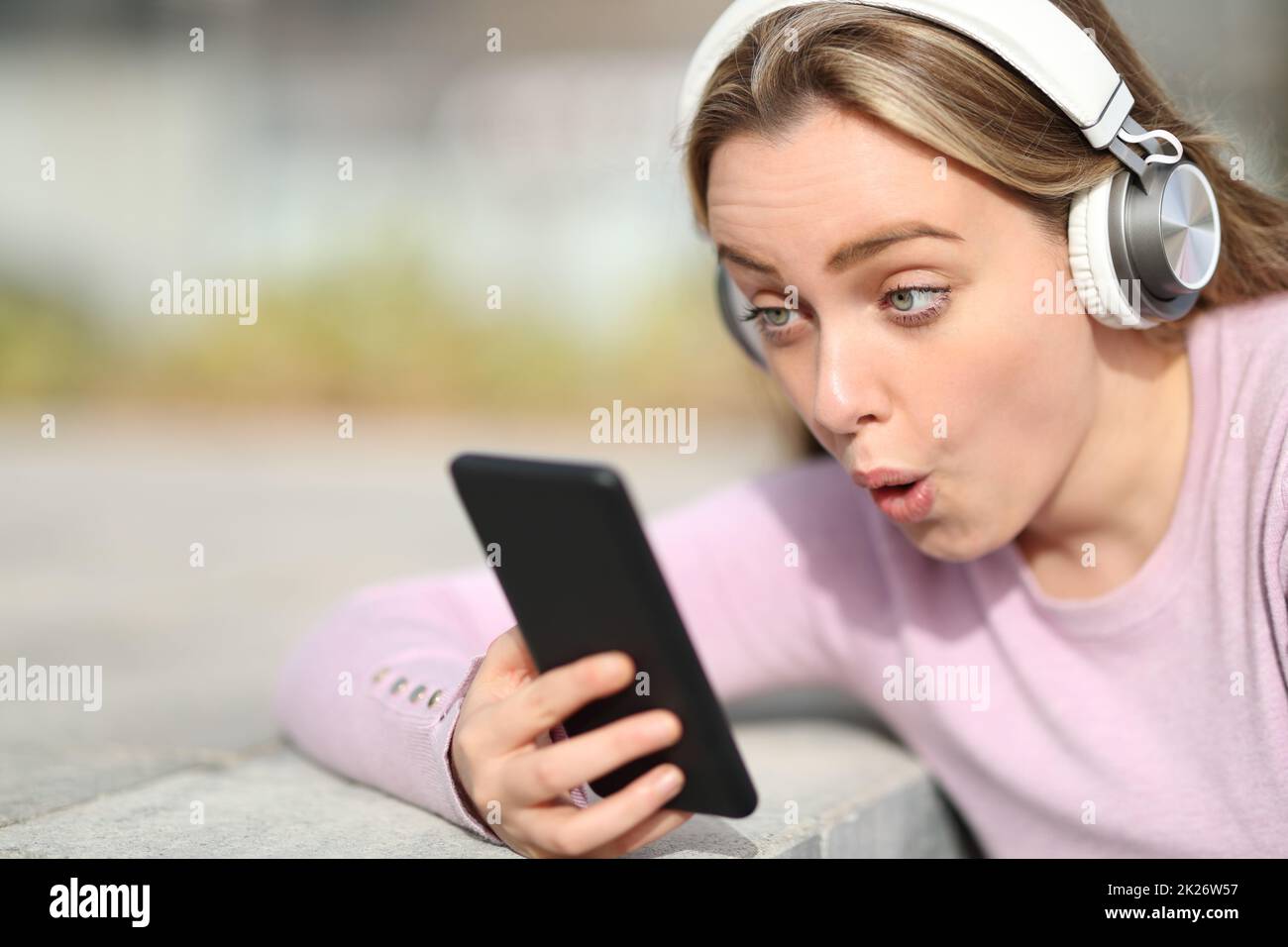 Surprised teenage girl checking phone audio content Stock Photo - Alamy