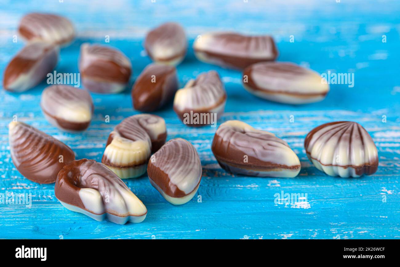 Chocolate candies sea shells on blue wooden background Stock Photo - Alamy