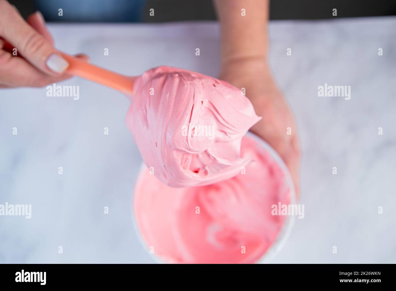 Pink confectionary meringue marengo is mixed in a white bowl on a white ...