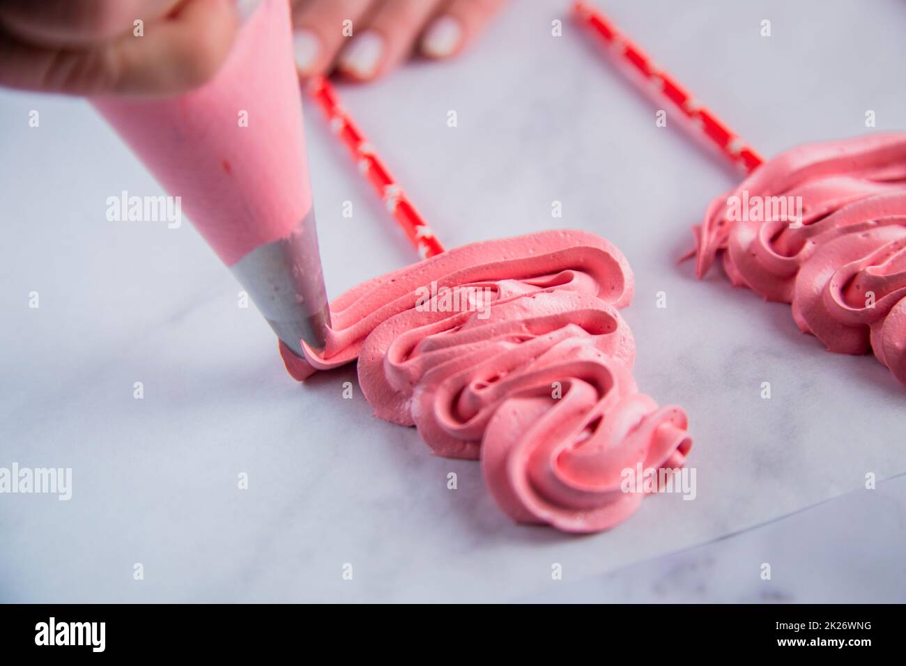 From the pastry bag, a pink bizet is laid out on baking paper with ...