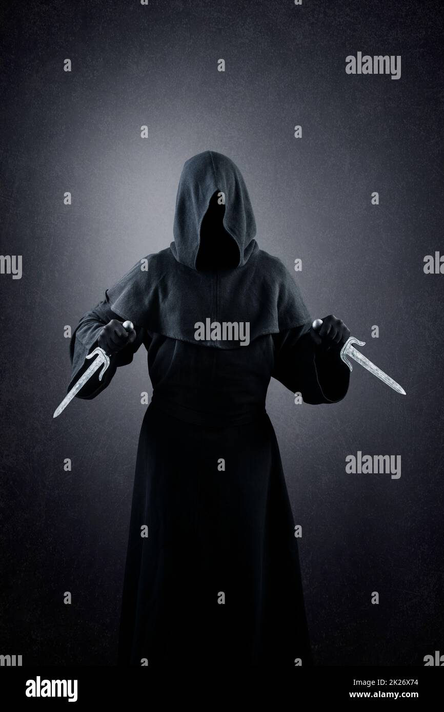 Hooded assassin with two daggers in the dark Stock Photo - Alamy