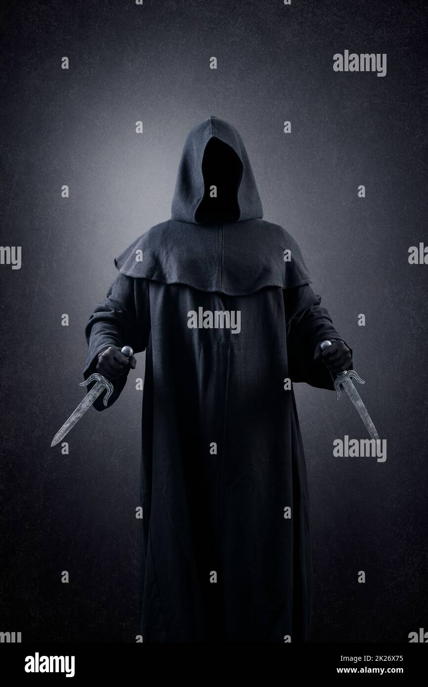 Hooded assassin with two daggers in the dark Stock Photo - Alamy