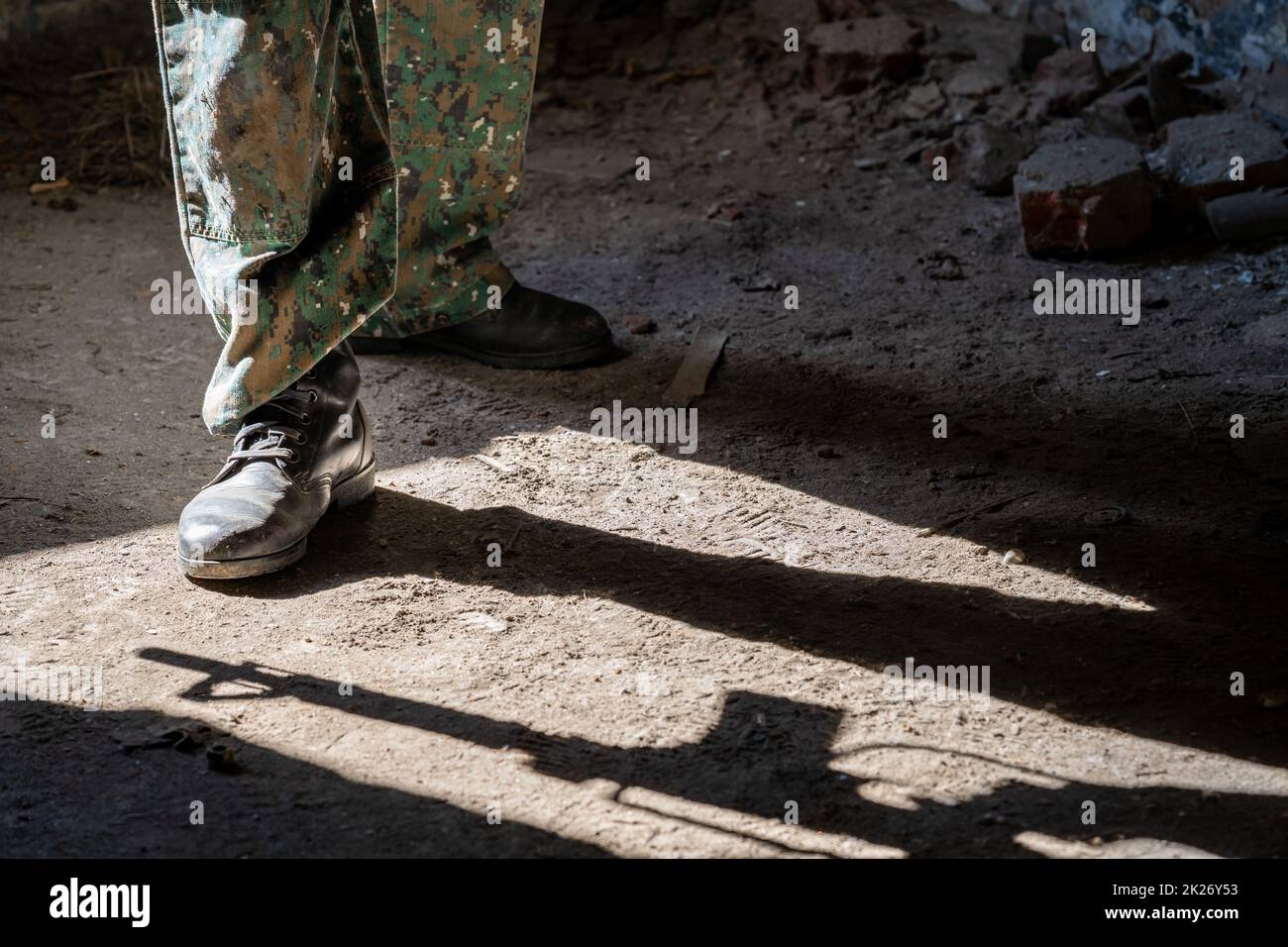 soldier in uniform, silhouette of a weapon as a shadow on the ground ...
