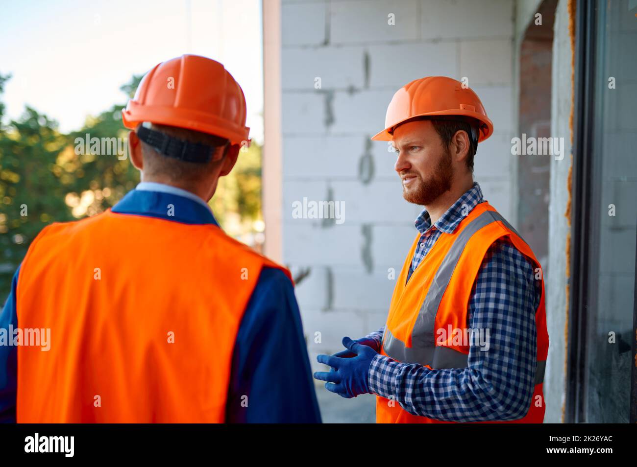 Two builder standing talking at construction site Stock Photo - Alamy