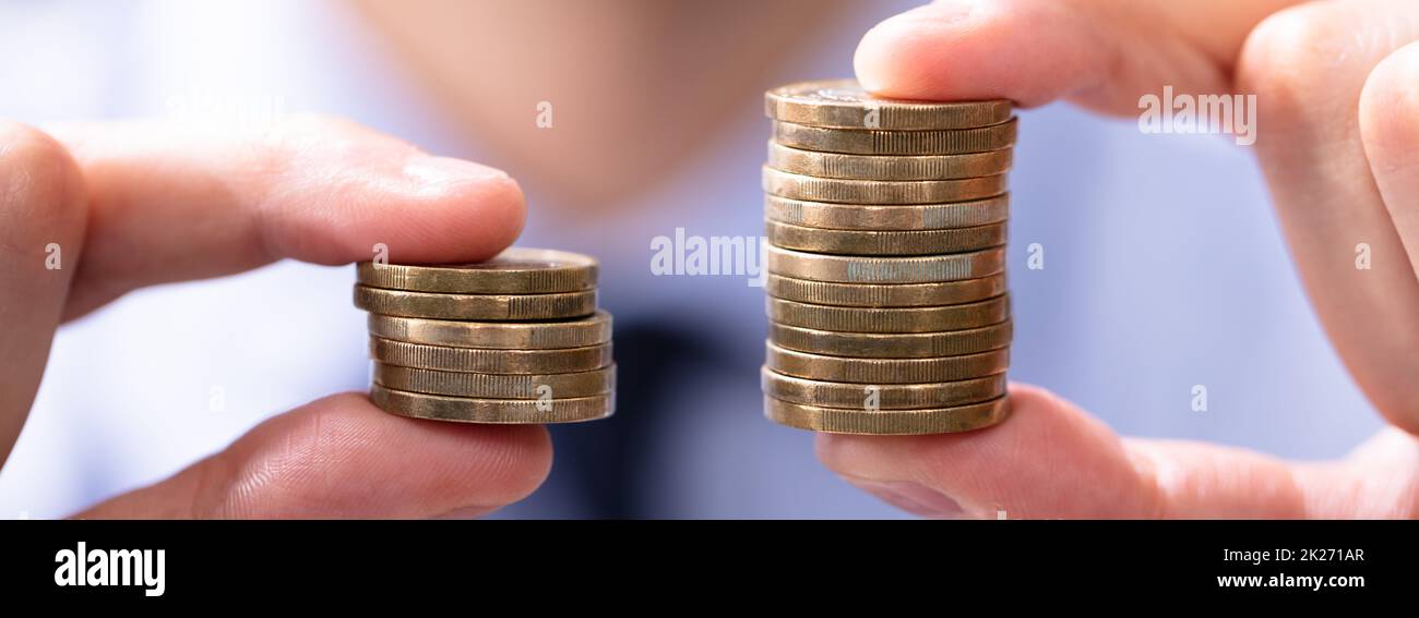 Man Comparing Two Coin Stacks Stock Photo - Alamy