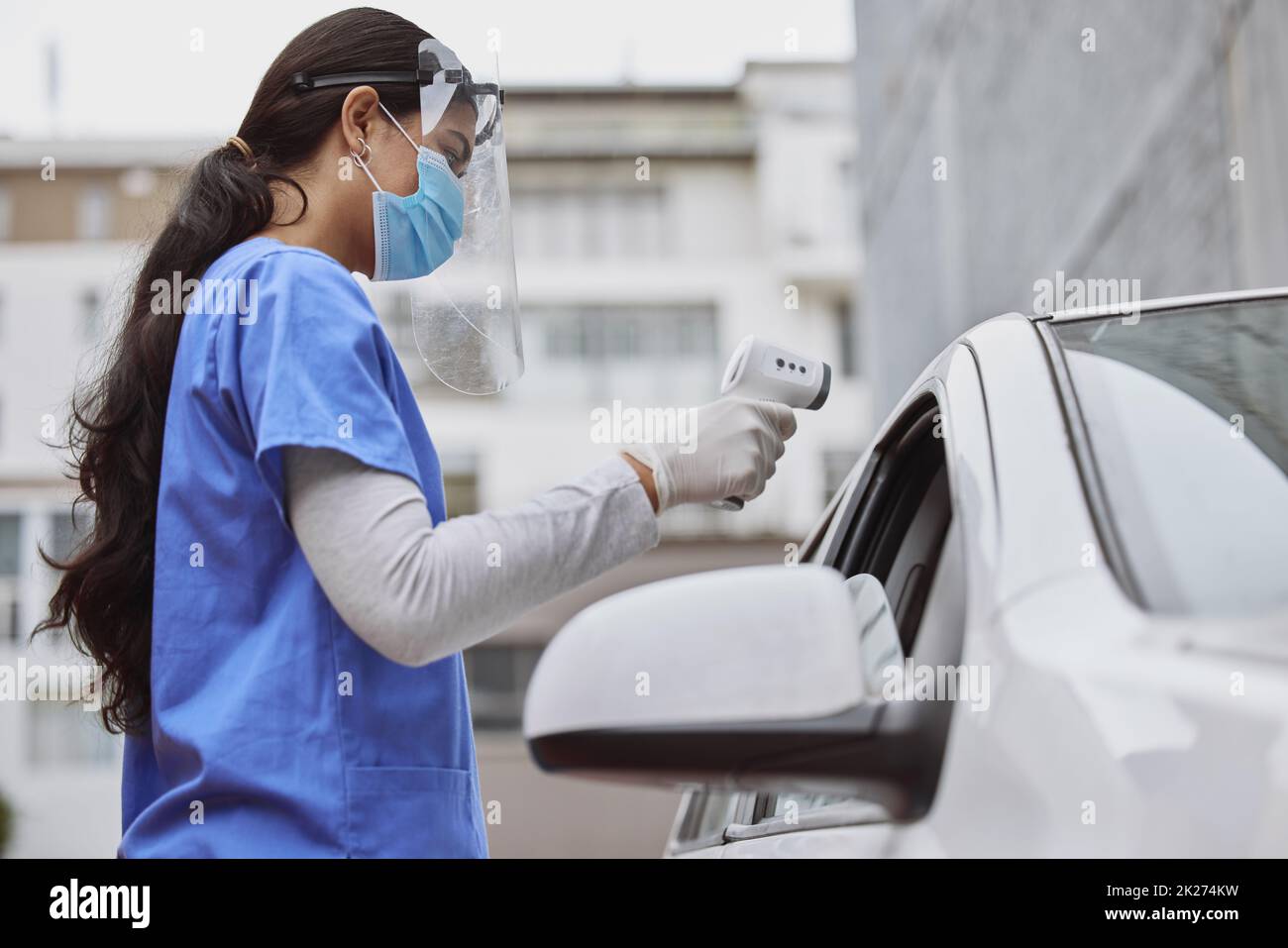 A quick temperature check. Shot of a young healthcare worker taking a ...