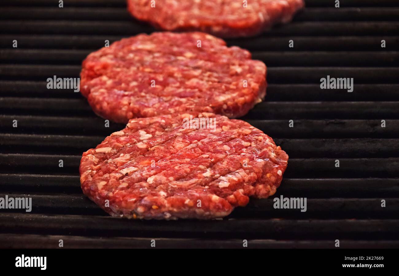 Raw beef burgers for hamburger on barbecue grill Stock Photo - Alamy