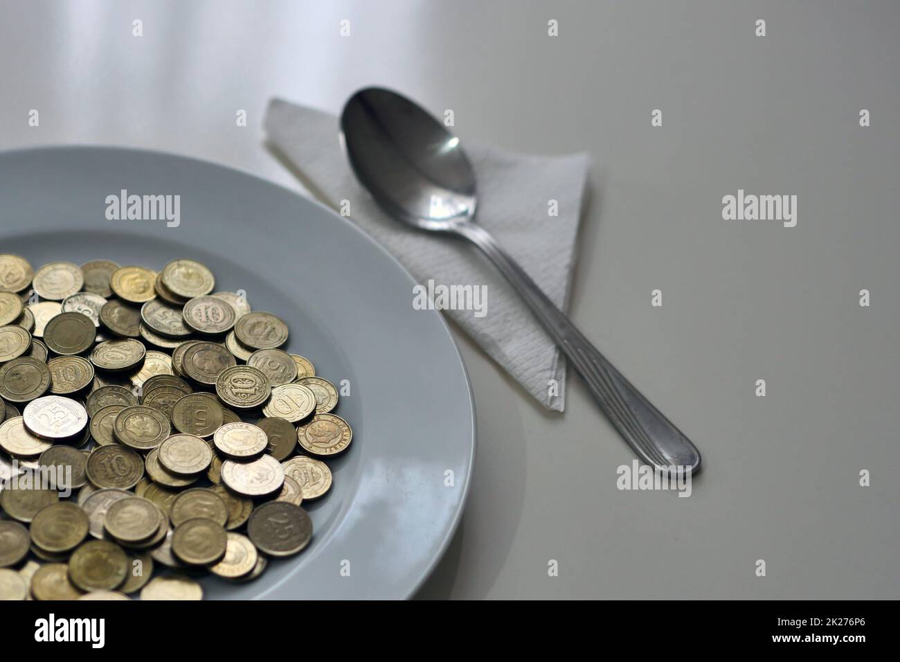 A plate full of coins on a table and a spoon next to it, eating money ...