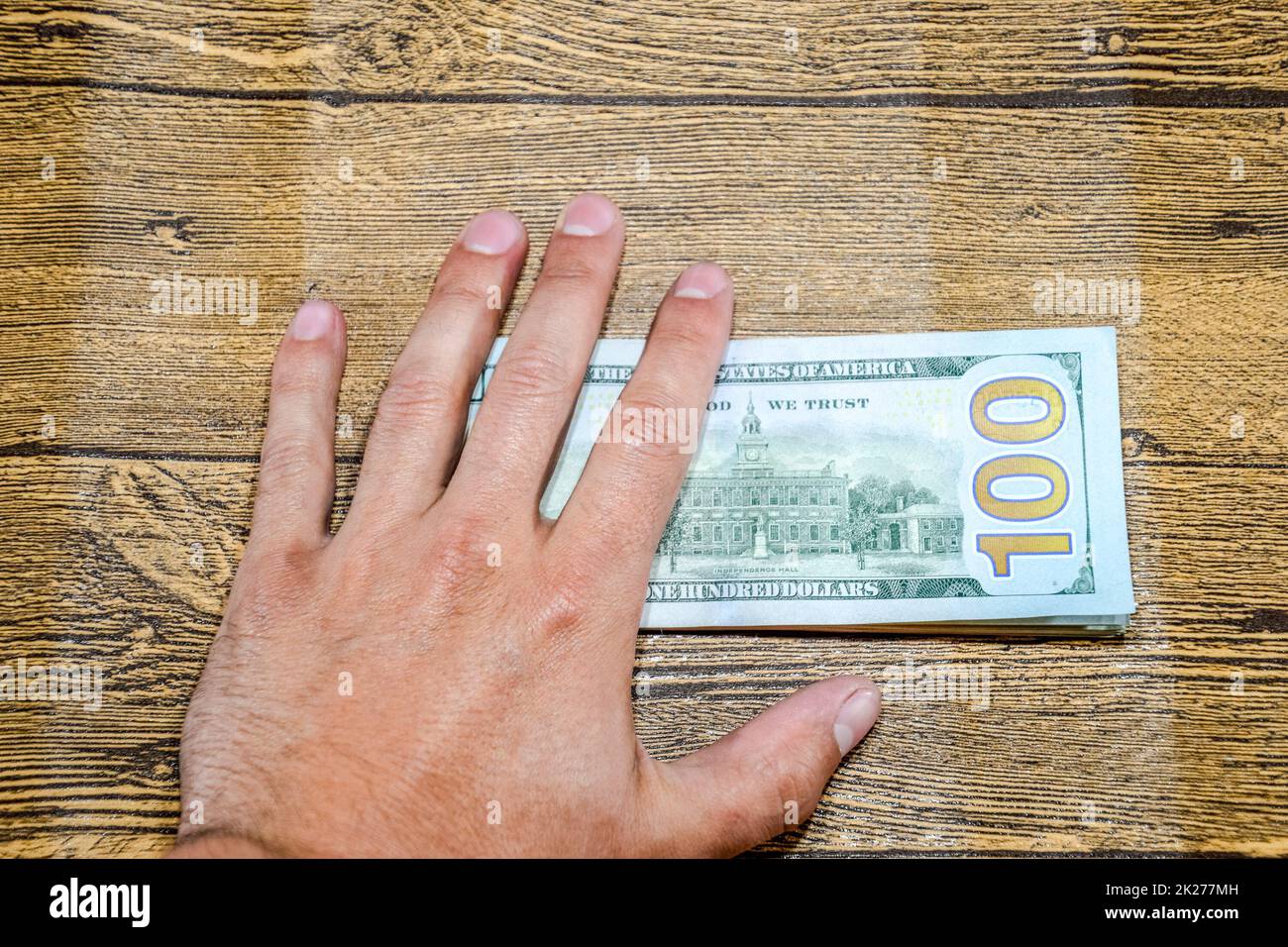 The man at table holds bills. Dollars in hand Stock Photo - Alamy