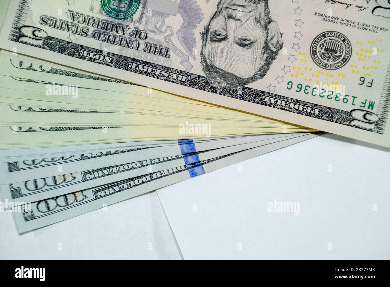 cistern of banknotes lies on a white table. Lots of dollars, a wad of ...