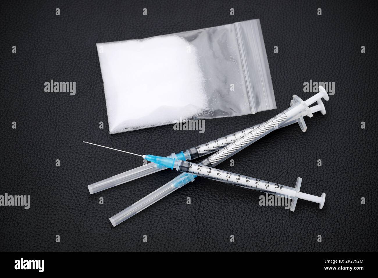 Drug injection syringe and cooked heroin in a bag on black background ...