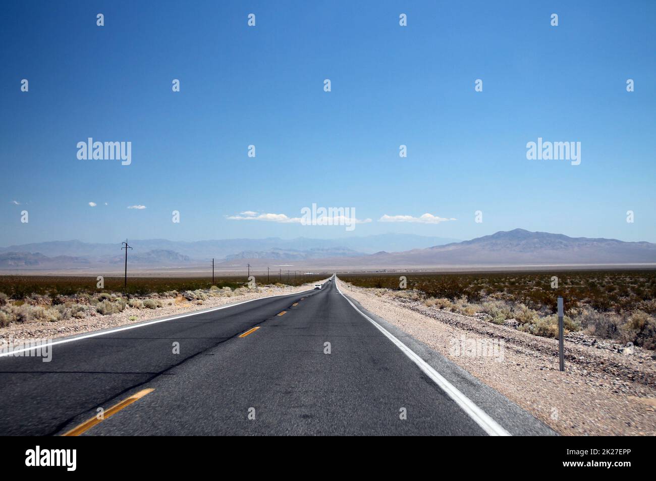 The Nevada Desert cut by a long infinite asphalt road under a clear ...