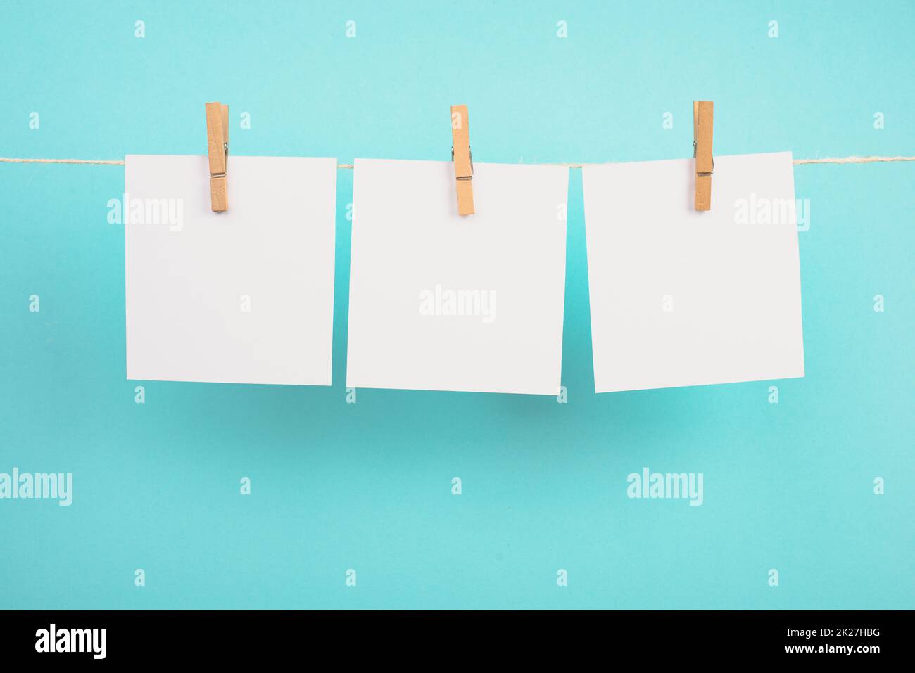 Empty white sheets of paper in a row hanging on a string, copy space ...