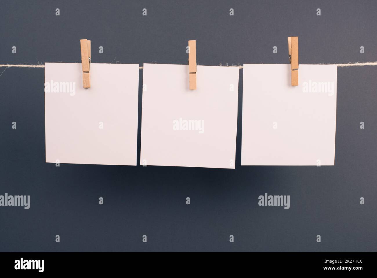 Empty white sheets of paper in a row hanging on a string, copy space ...