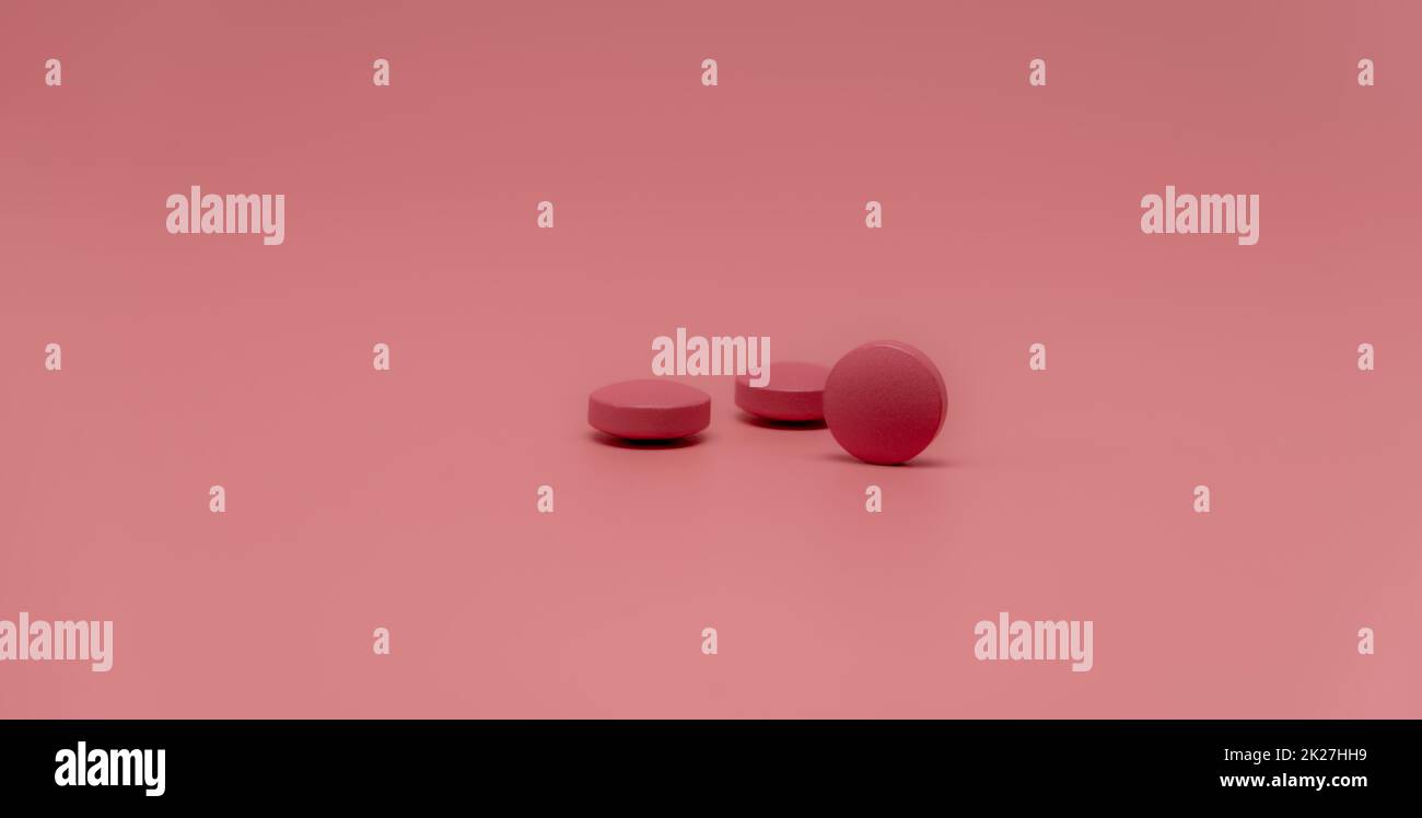 Selective focus on round pink tablet pill on pink background. Pharmacy ...