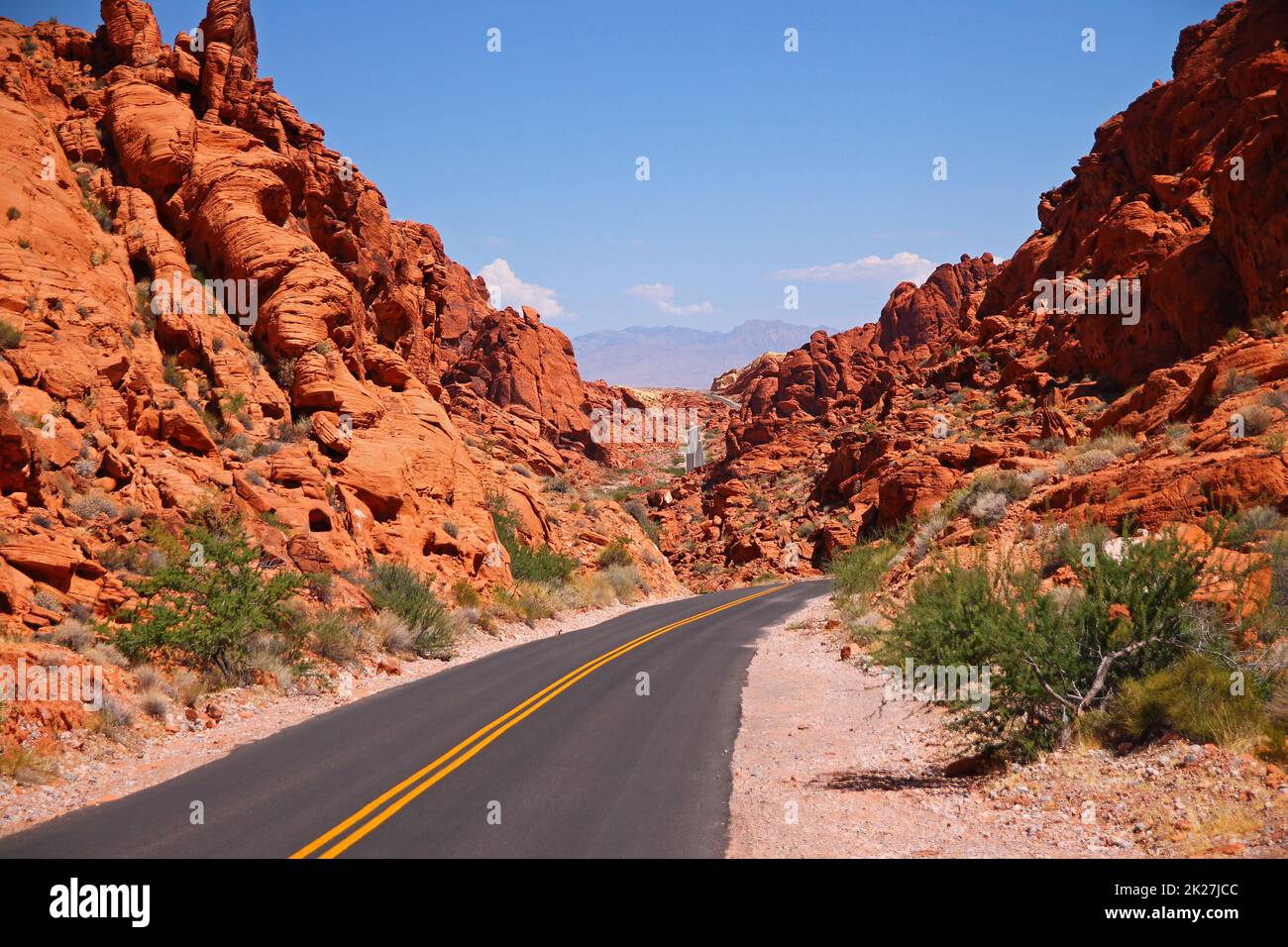 The asphalt road in the middle of the valley surrounded by red rocks ...