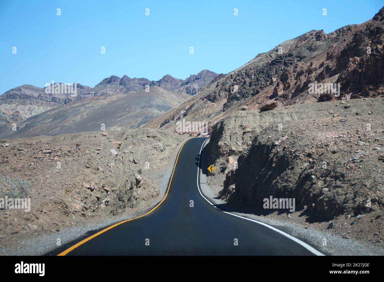 The dip in the black road on the rock formations of the desert Stock ...