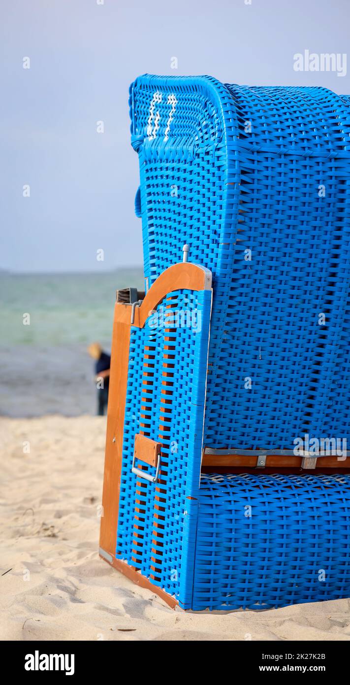 A blue beach chair stands on the Baltic Sea beach and is waiting for ...
