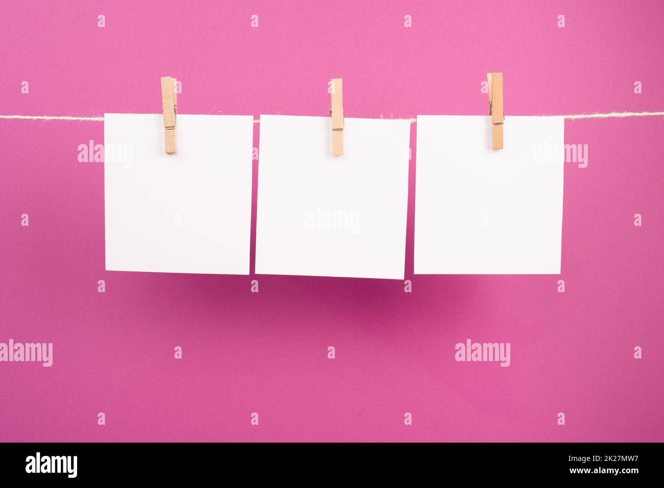 Empty white sheets of paper in a row hanging on a string, copy space ...