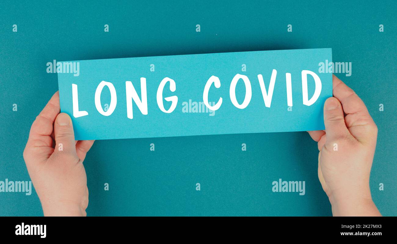 The words long covid are standing on a paper, hands hold the message ...