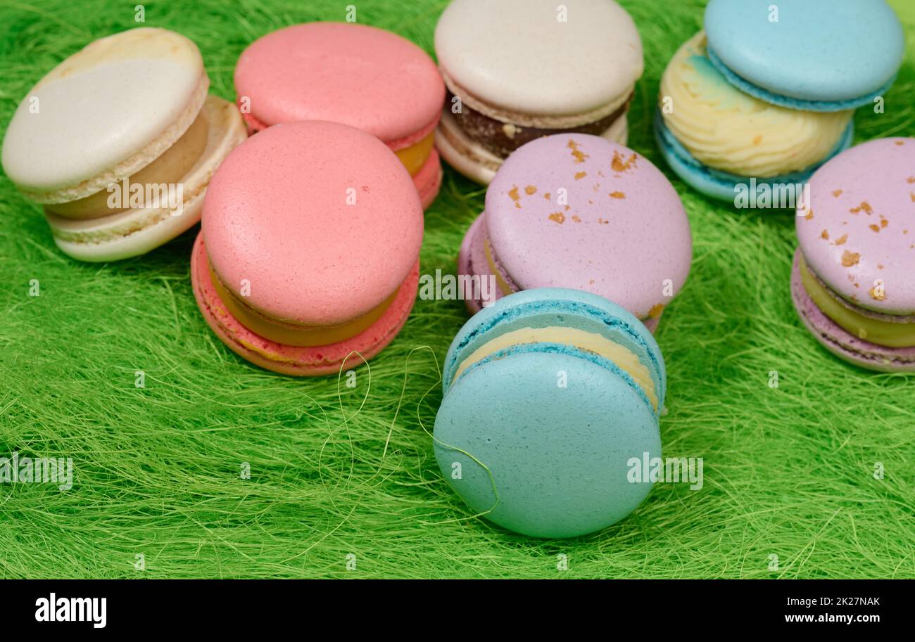 baked macarons with different flavors on a green background, top view ...