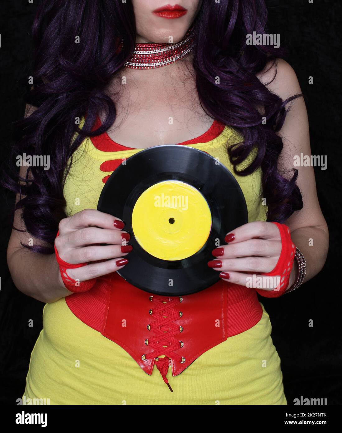 Woman in 1980s yellow clothing holding 45rpm record. Record label ...